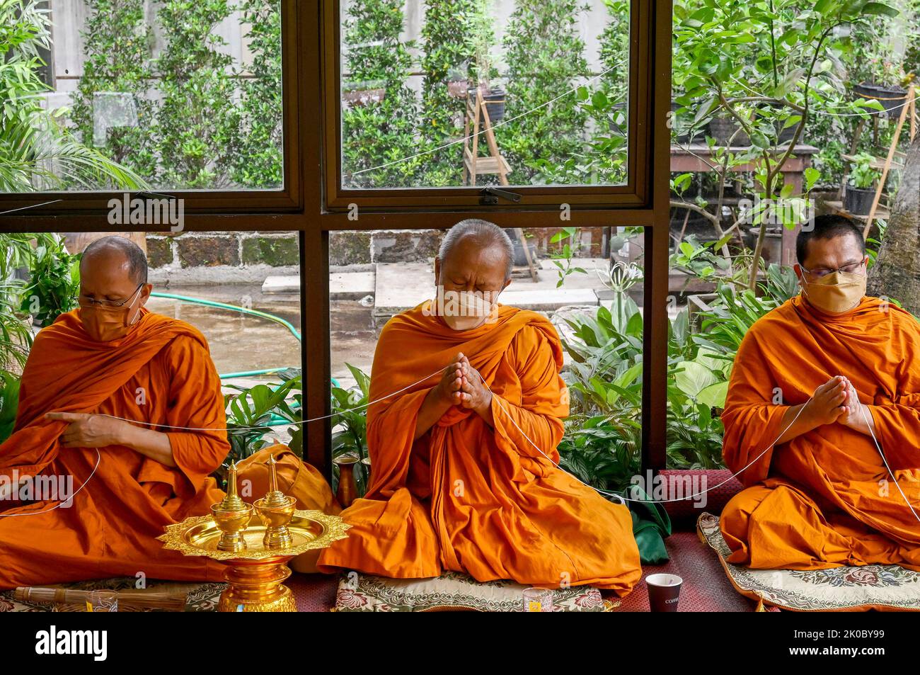 A close up view of Thai monks holding sai sin, blessed white string ...