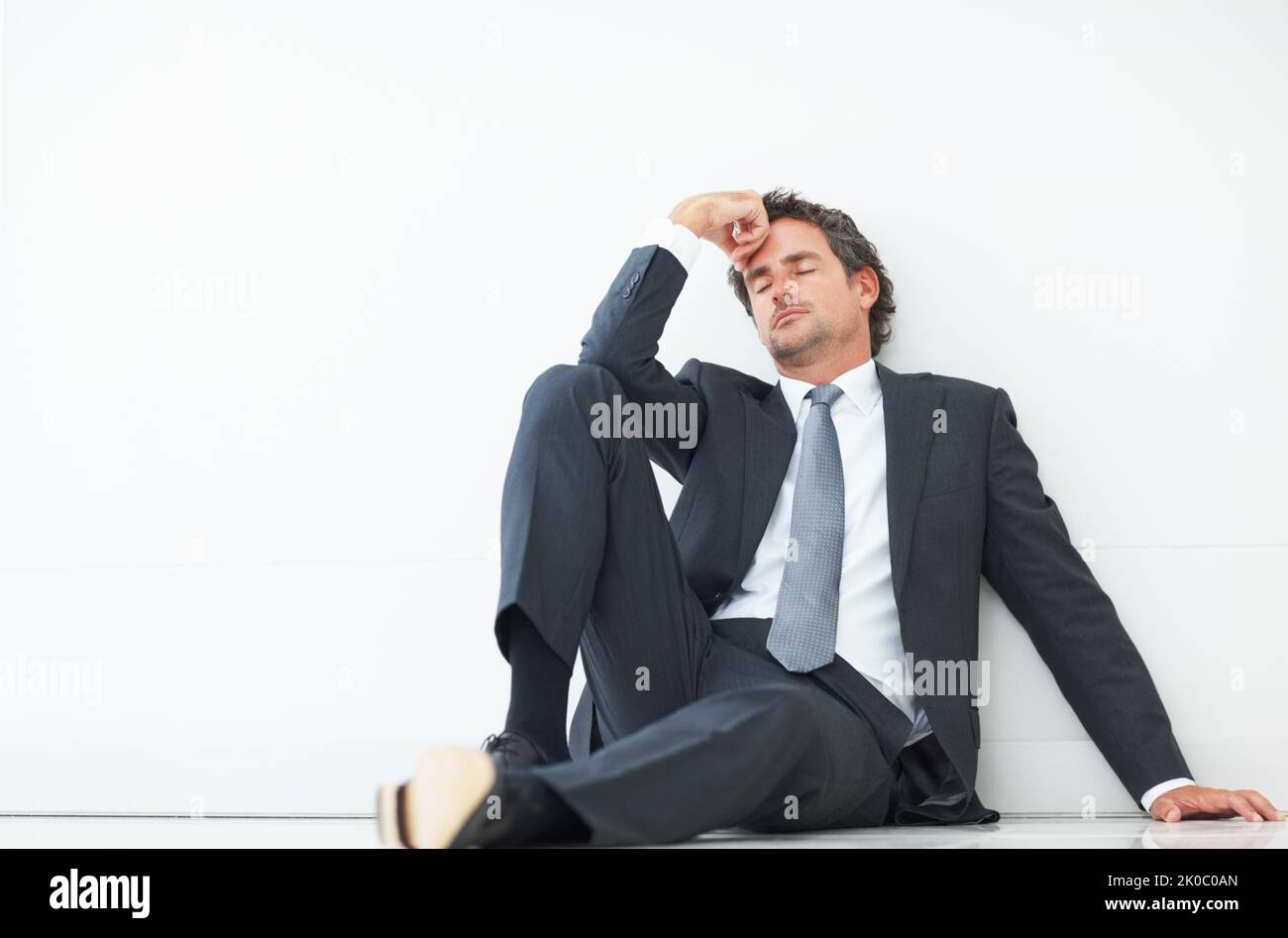 Quick nap. Handsome business man taking a quick nap sitting against ...