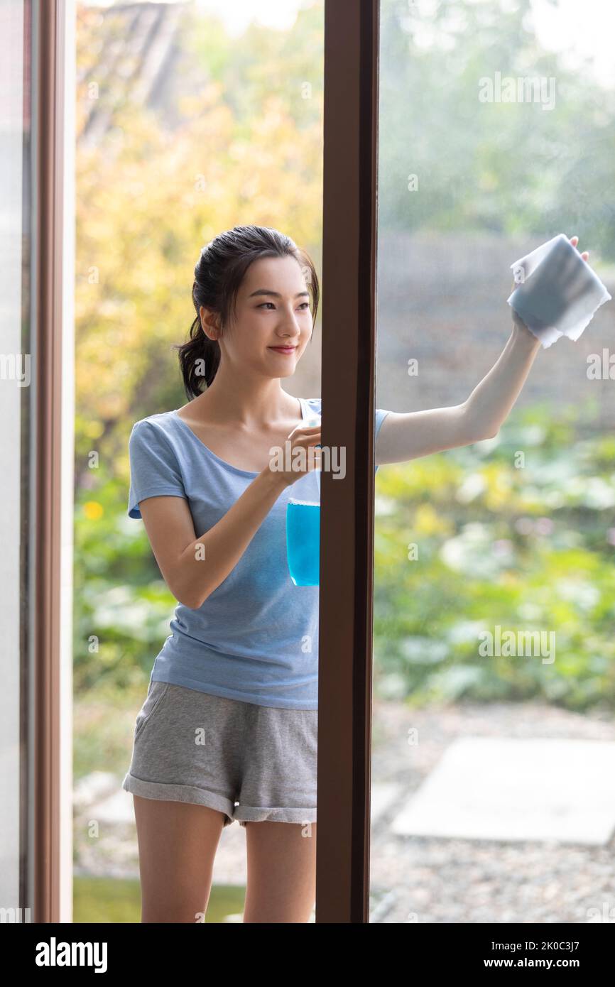 Cheerful young Chinese woman doing housework Stock Photo - Alamy