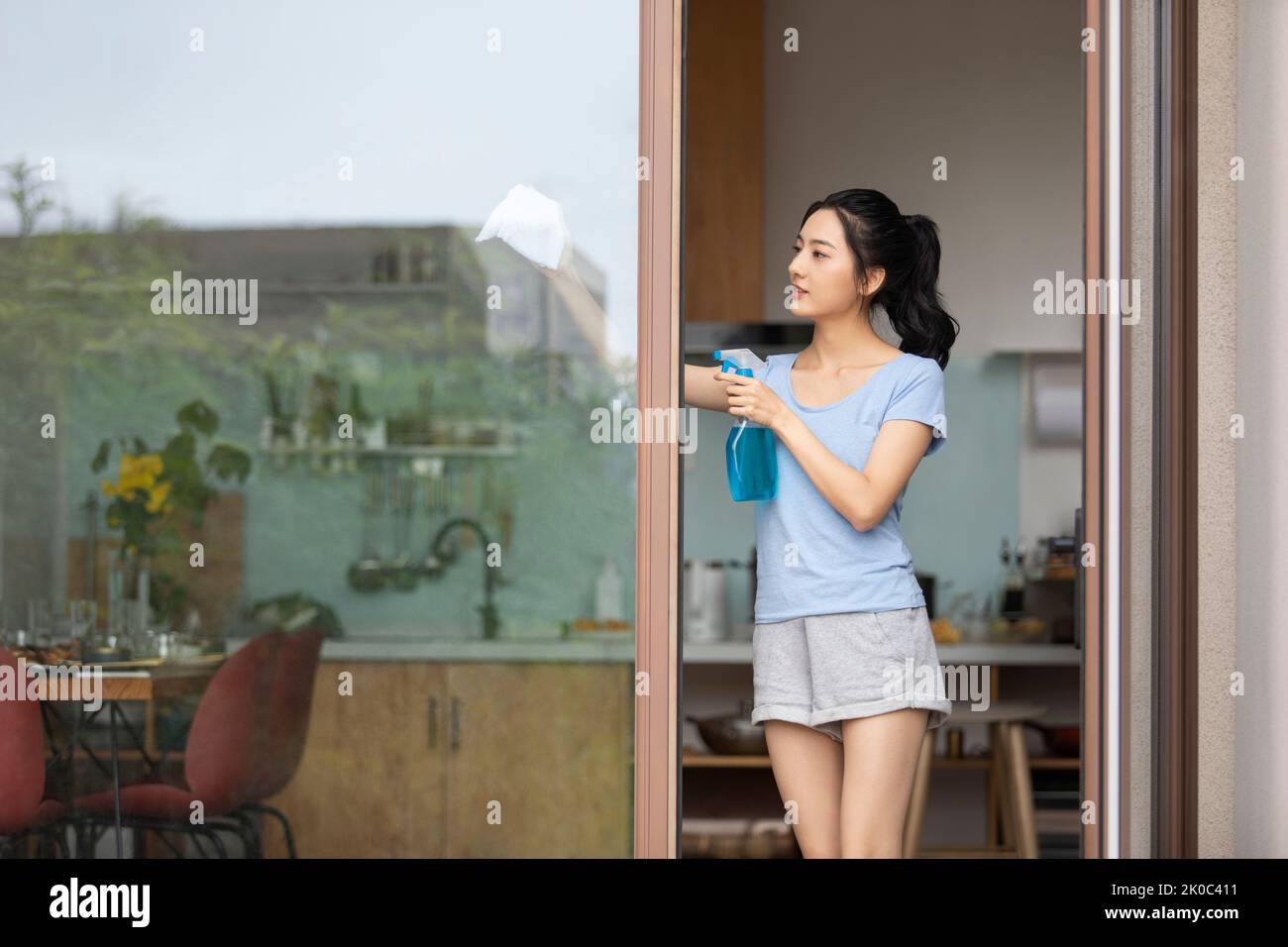 Cheerful young Chinese woman doing housework Stock Photo - Alamy
