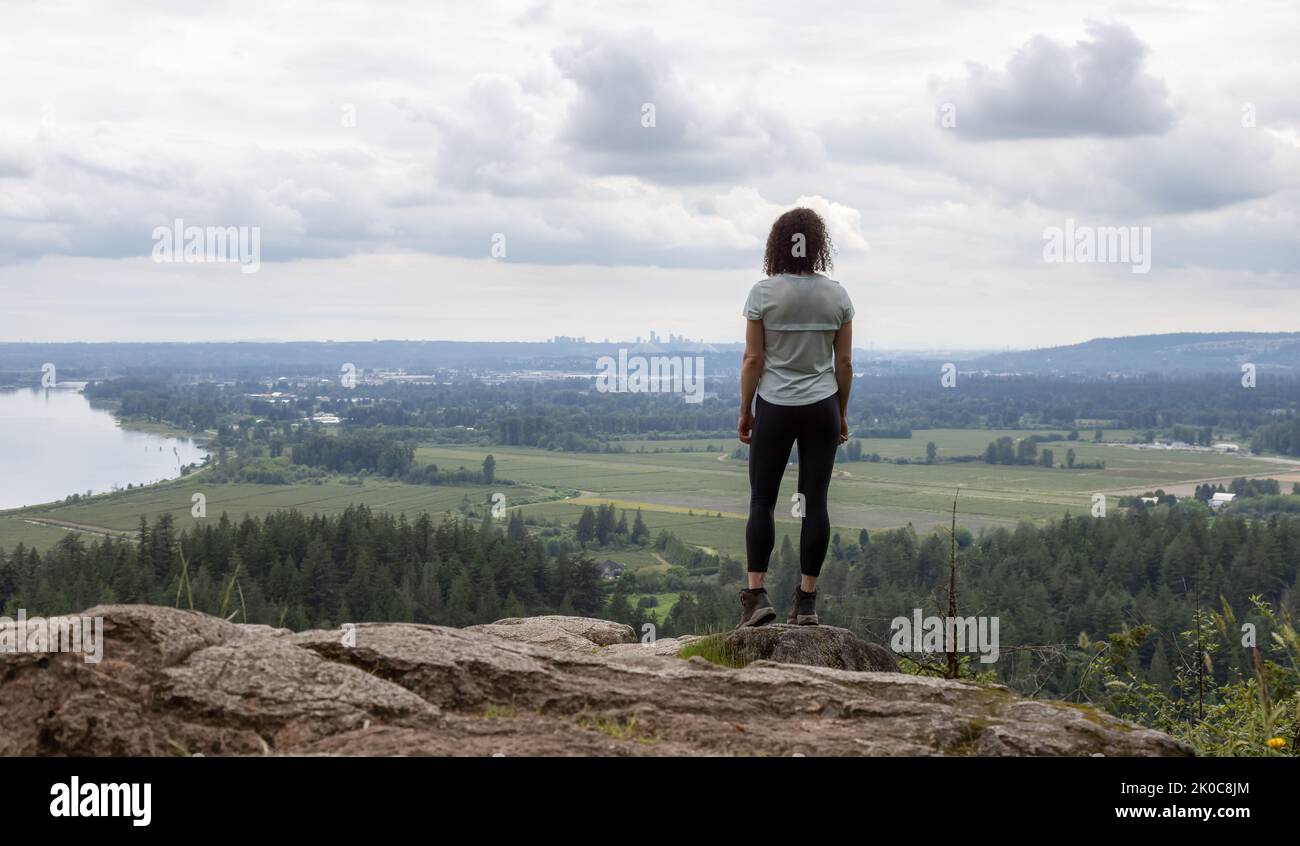 Adventurous Woman Standing on top of a rock overlooking the Canadian ...