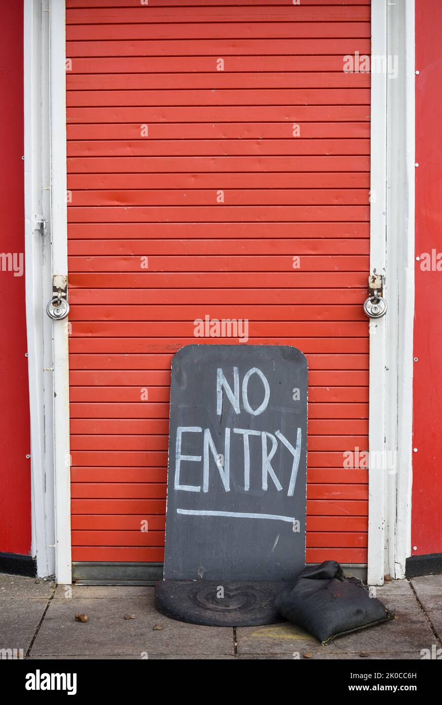 Hand written no entry on a black board in front of a bright red door ...