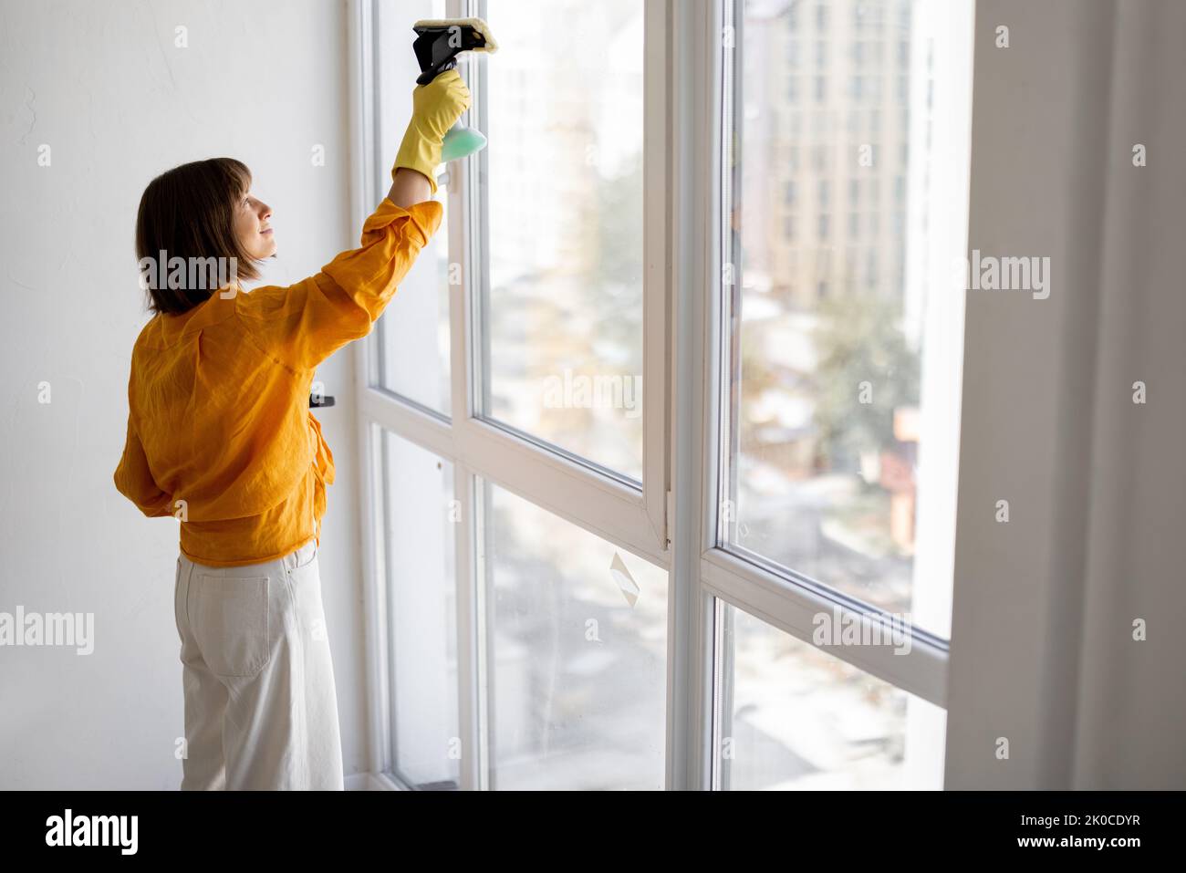 Woman washes window in apartment Stock Photo - Alamy