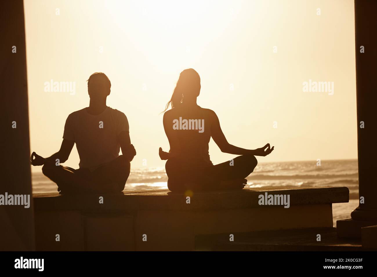 Meditating in beautiful surroundings. a couple meditating by the sea at ...