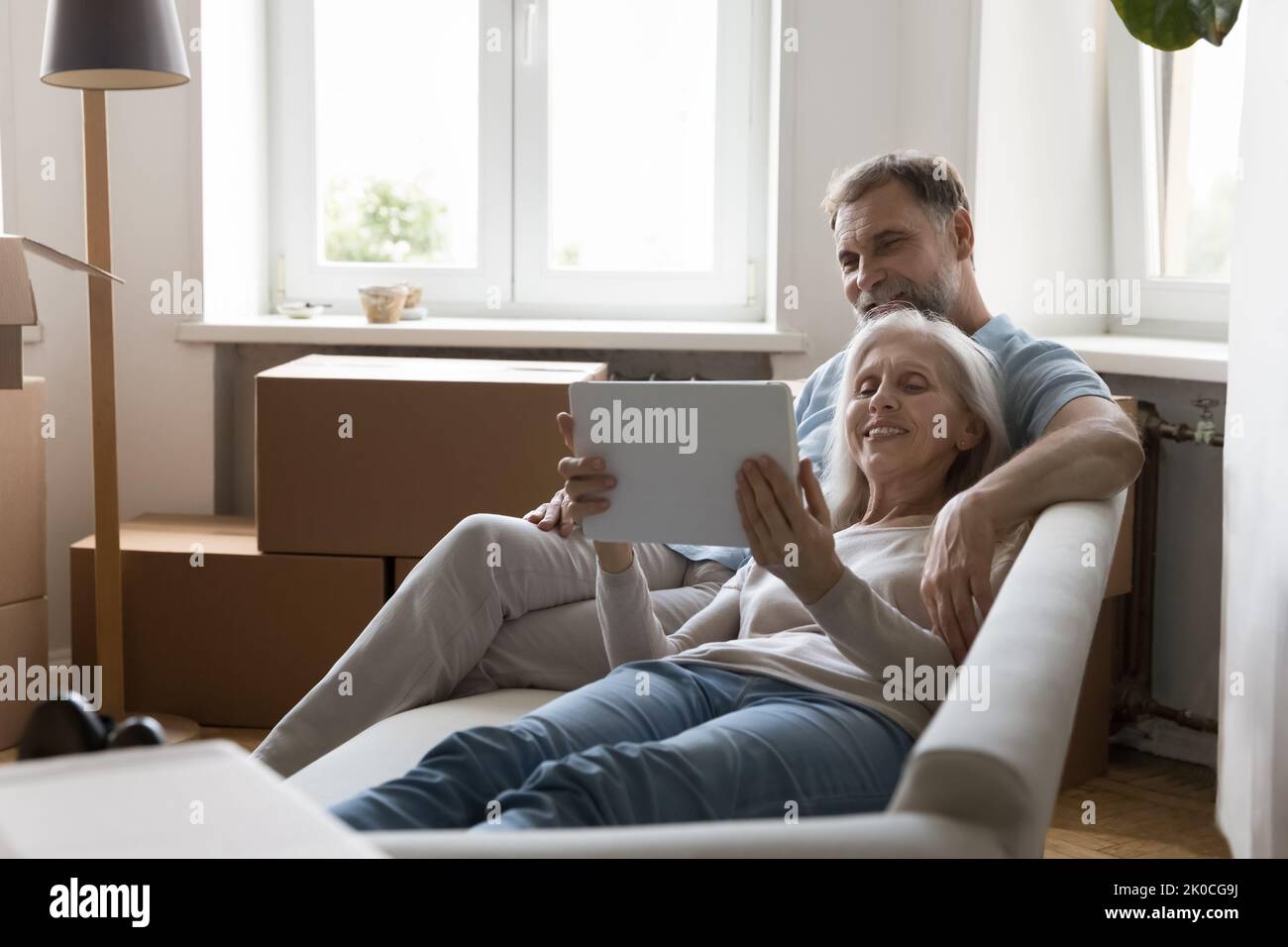 Happy senior family couple relaxing on sofa after moving activities ...