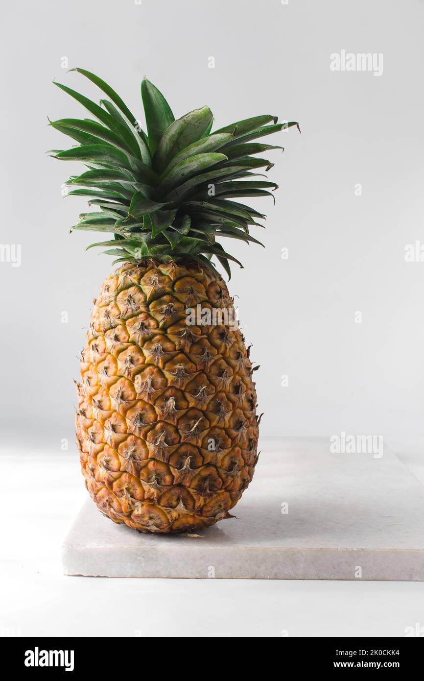 A Whole pineapple on a white chopping board large pineapple Stock Photo ...