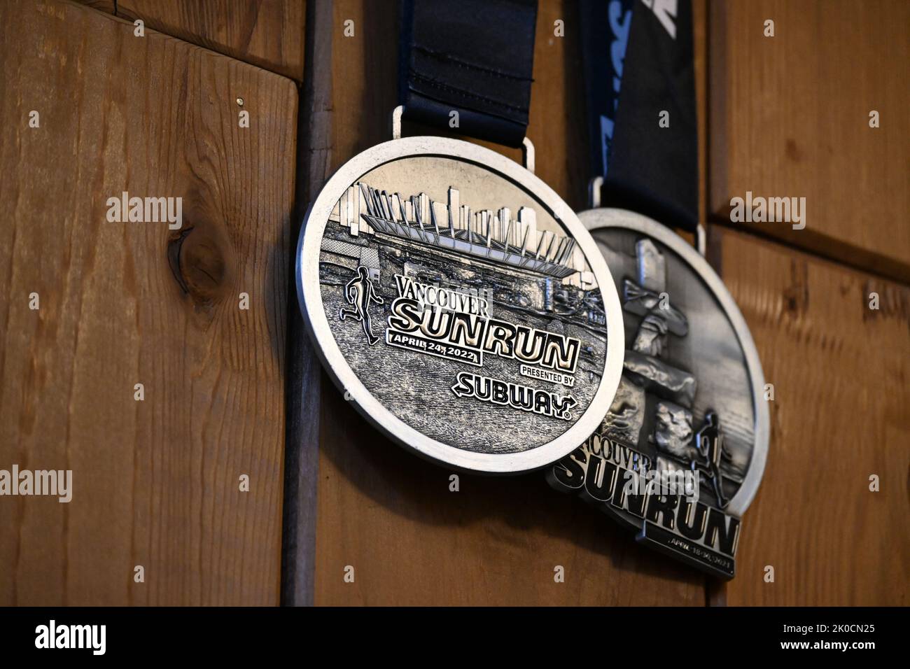 Vancouver Sun Run medals hanging on a wood wall Stock Photo - Alamy