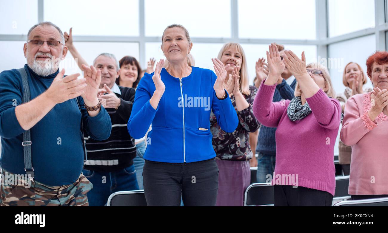 a group of elderly people are sitting in a circle clapping their Stock ...
