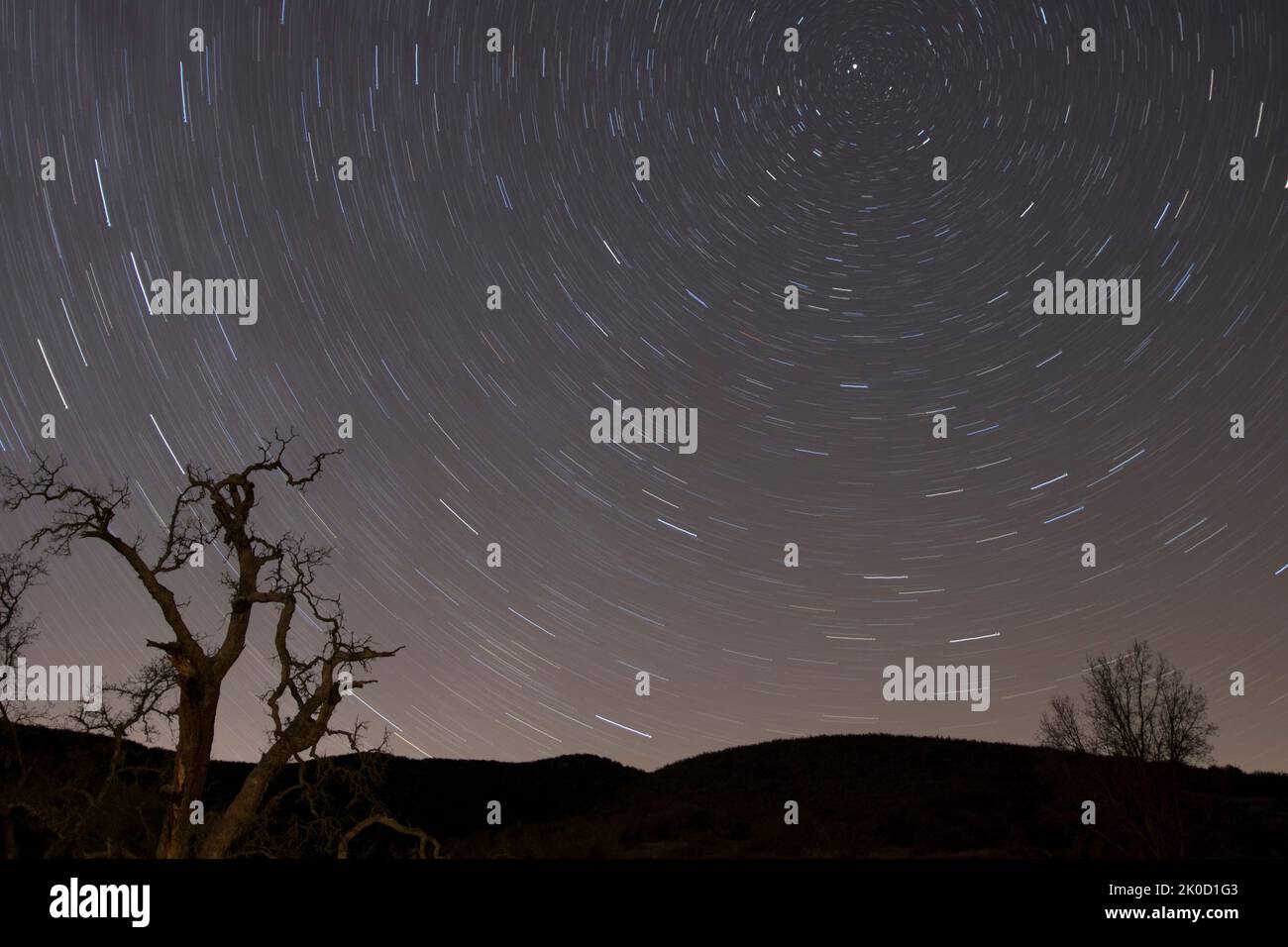 A long exposure shot of a star-filled night sky, featuring silhouette ...
