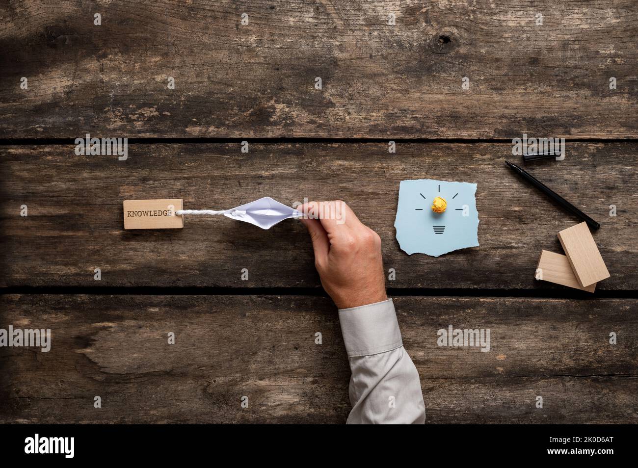 Male hand pulling an origami made paper boat with a Knowledge sign ...