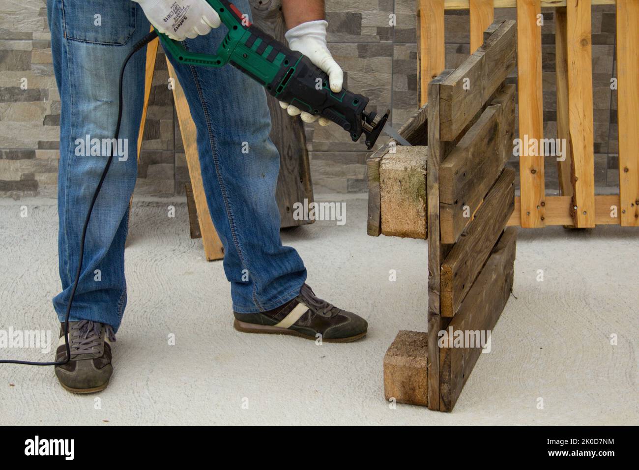 Image of the hands of a construction worker who cuts pallets of pallets ...