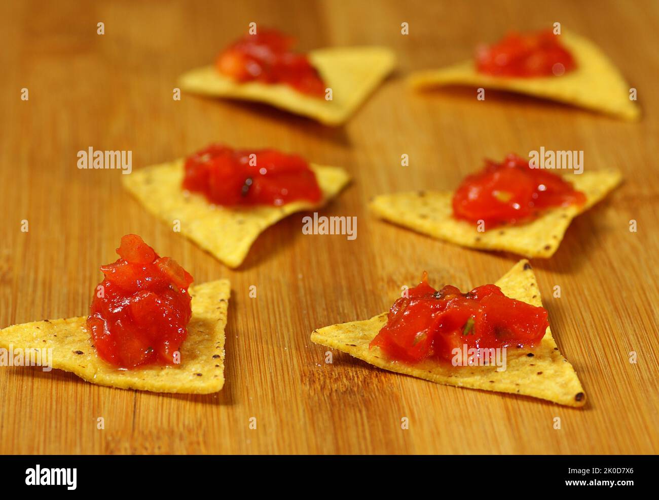 individual nachos on a wooed board with salsa topping Stock Photo - Alamy