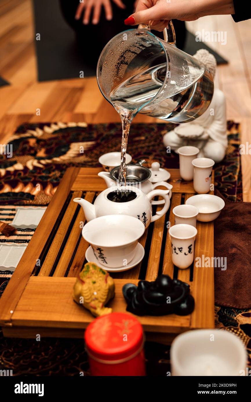 Chinese tea ceremony. A woman pours water from a jug into a kettle ...