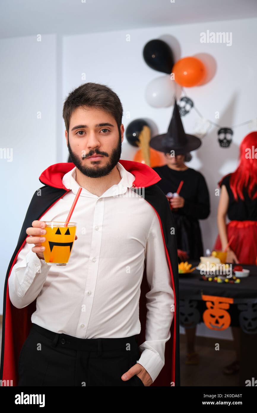 Serious young man dressed as vampire with a cocktail at costume ...