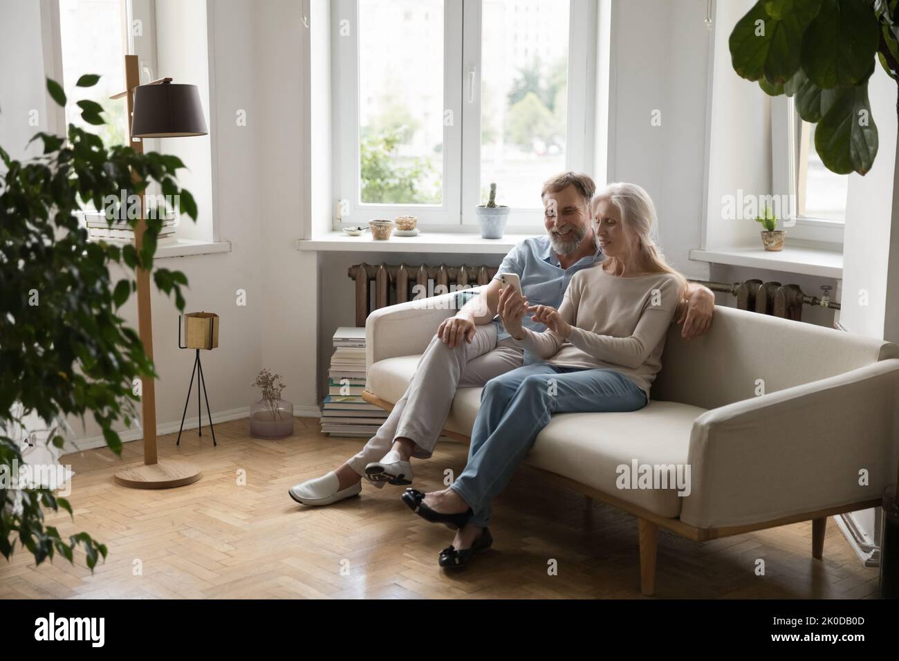 Happy retired couple sitting on couch in new home interior Stock Photo ...