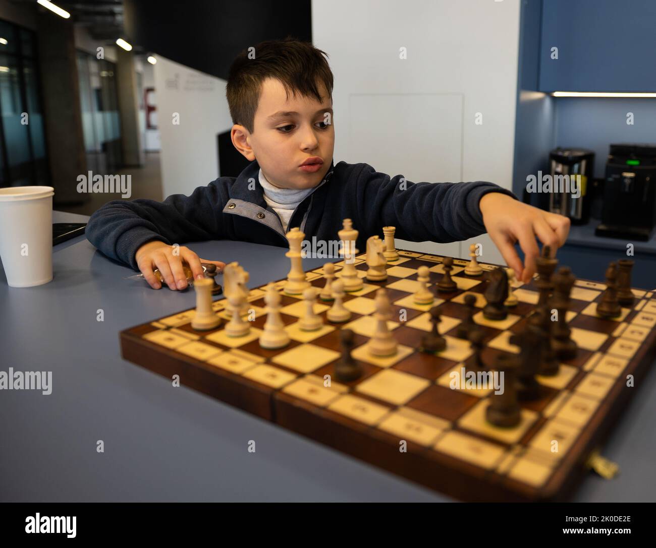 Adorable smart elementary age boy thinking on chess move, developing ...