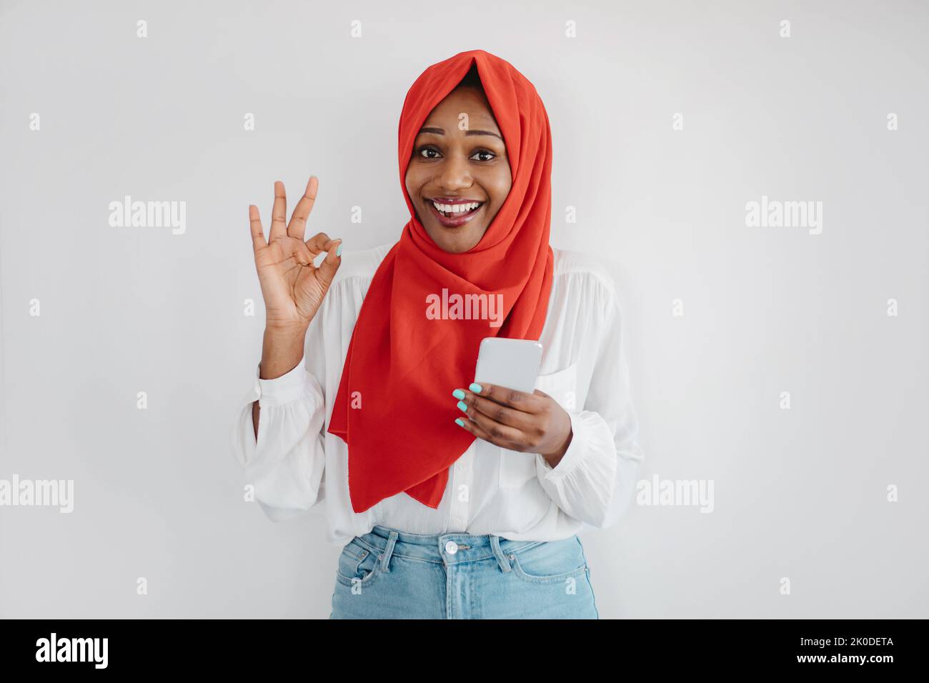 Great app. Excited black muslim woman in hijab using smartphone and ...