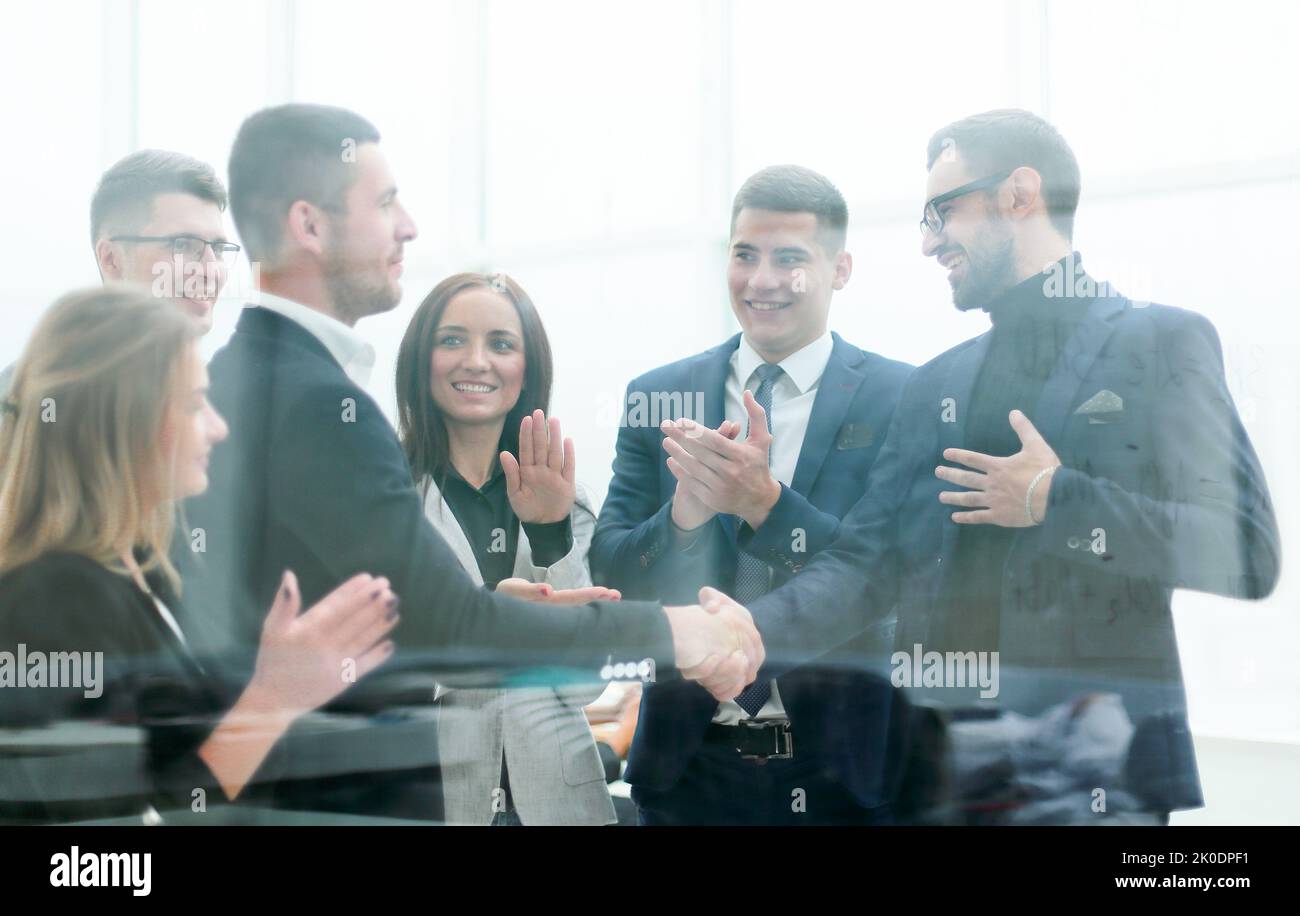 through the glass. business people meet each other with a handshake ...