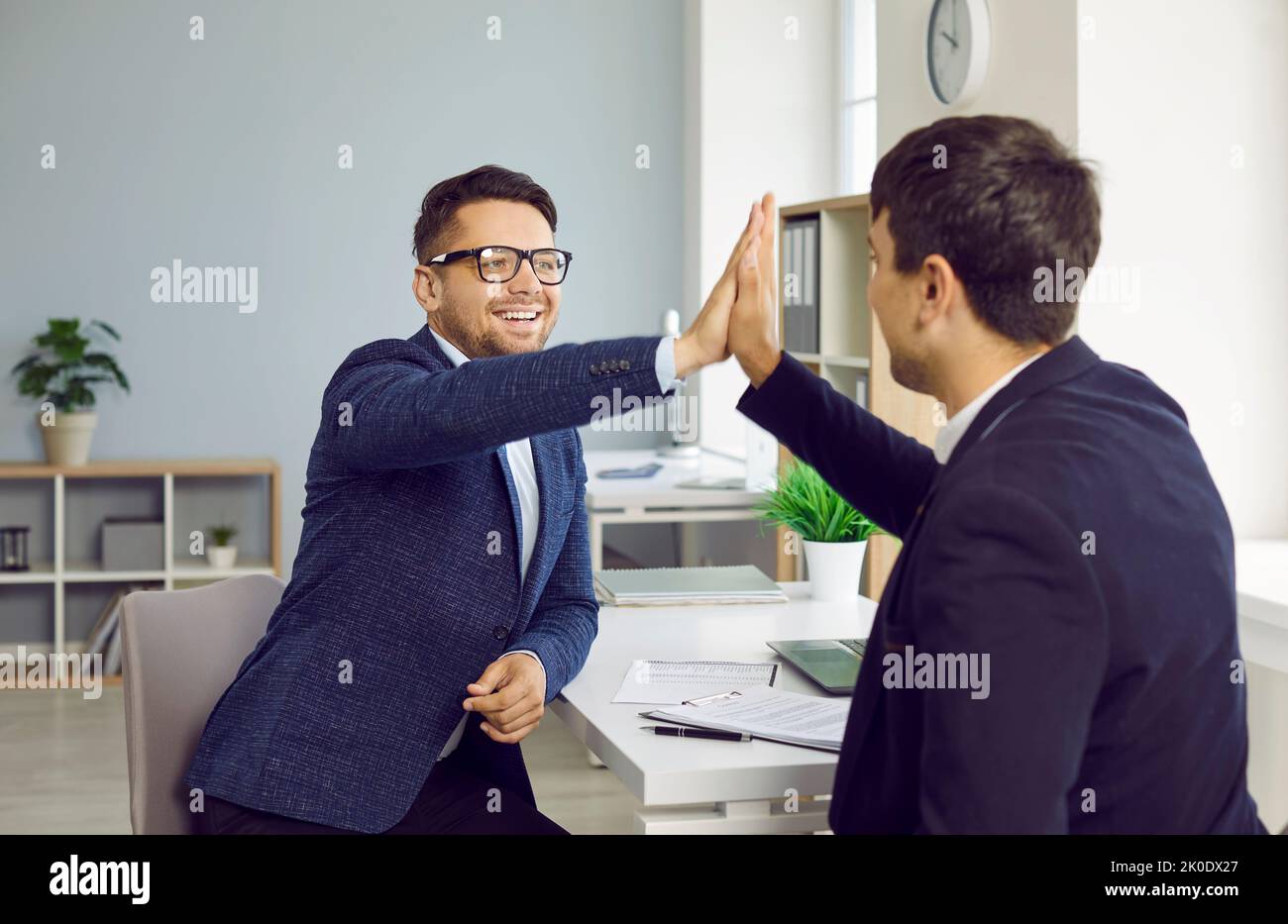 Two colleagues give each other high five in celebration of job well ...