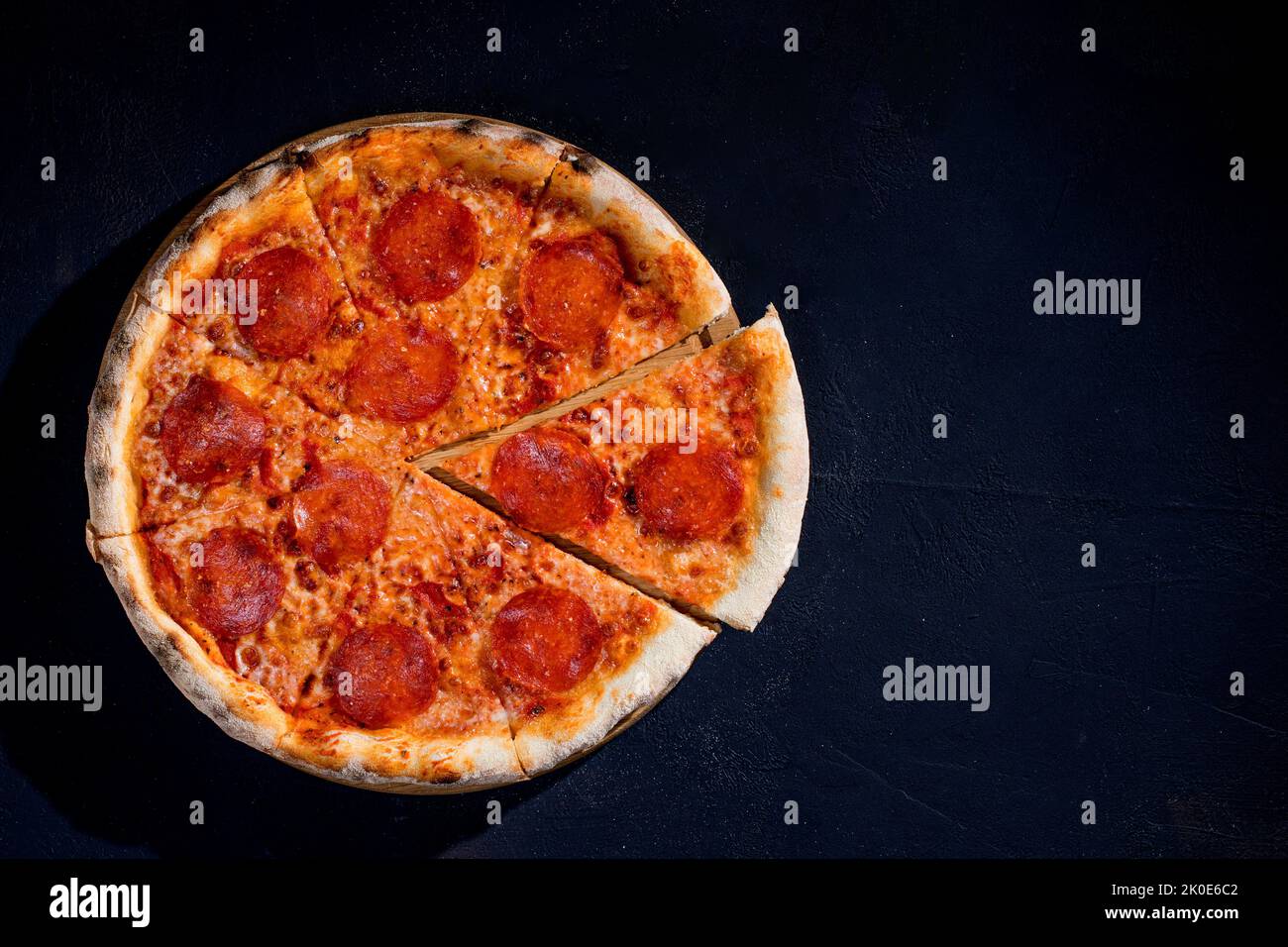 Pizza with tomato sauce, mozzarella, salami on black background. View ...