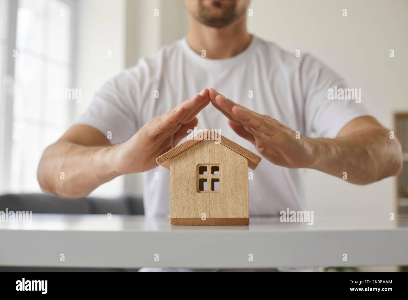 Man makes roof protection over small house with his hands, symbolizing ...