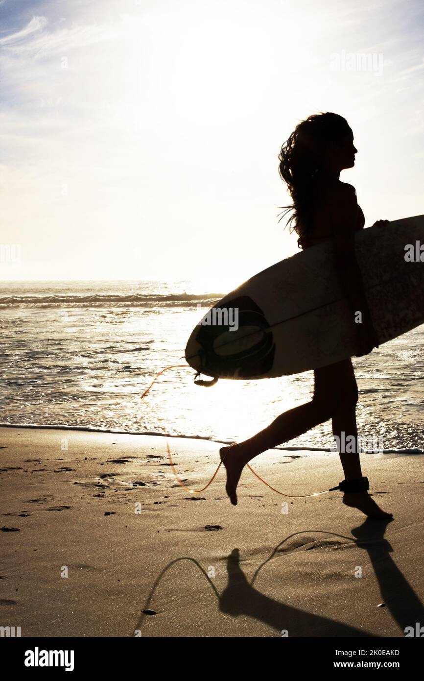 Pretty young female surfer with her surfboard. Young female running ...