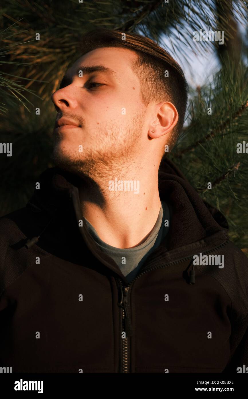 A portrait young man with gray hair walks through a forest and enjoys a ...