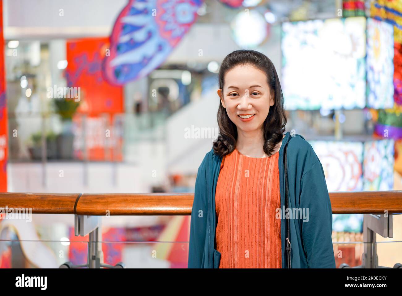 Woman wearing orange shirt and blue jacket put her hand in the pocket ...