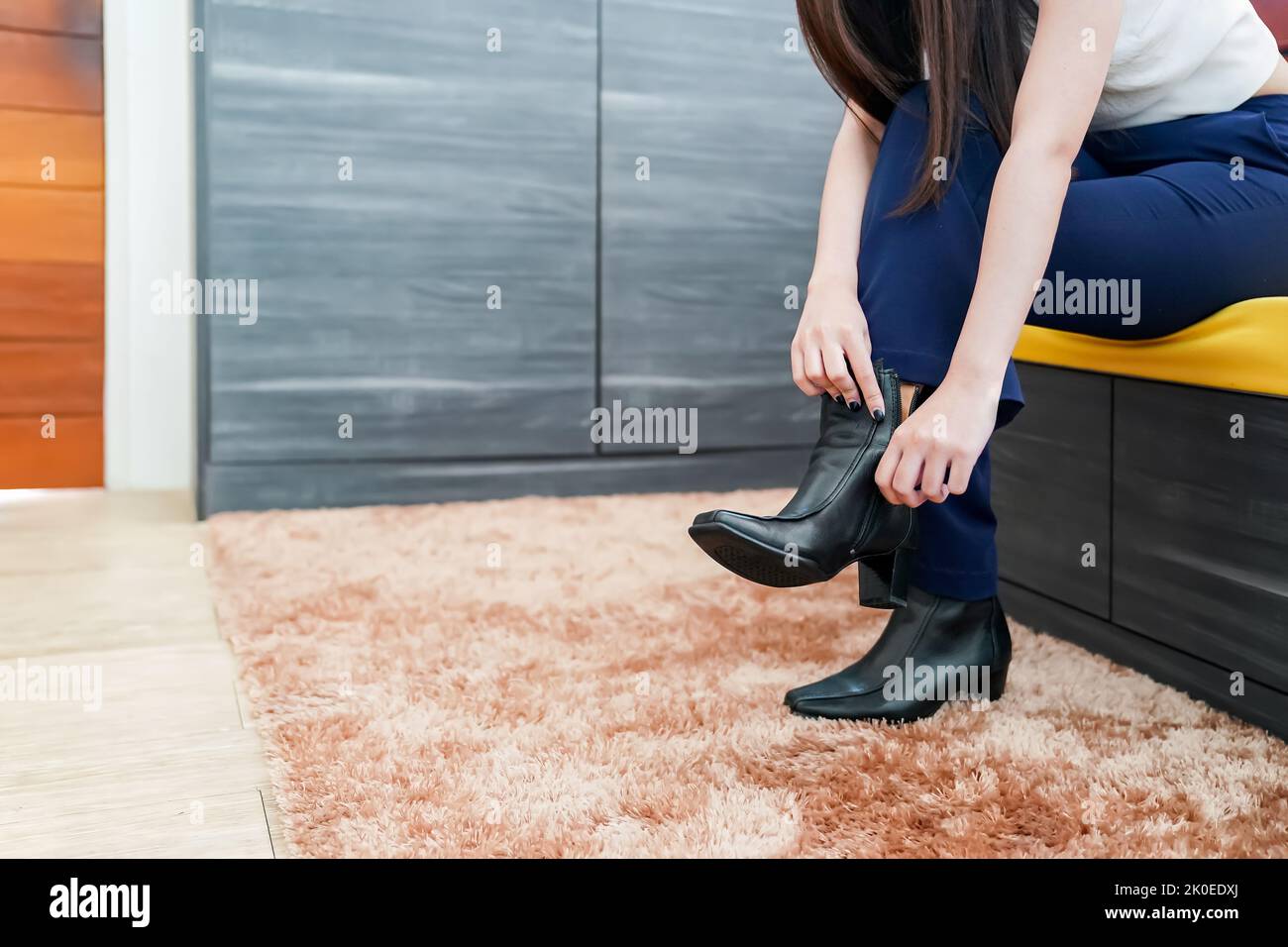 A woman is trying on leather black shoes in a shoe store with a brown ...