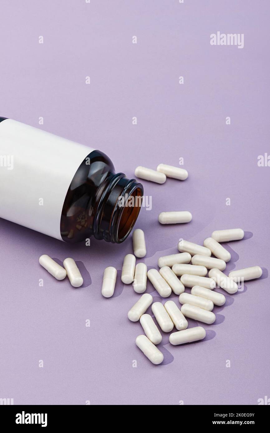 Capsules scattered next to a jar with an empty label Stock Photo - Alamy