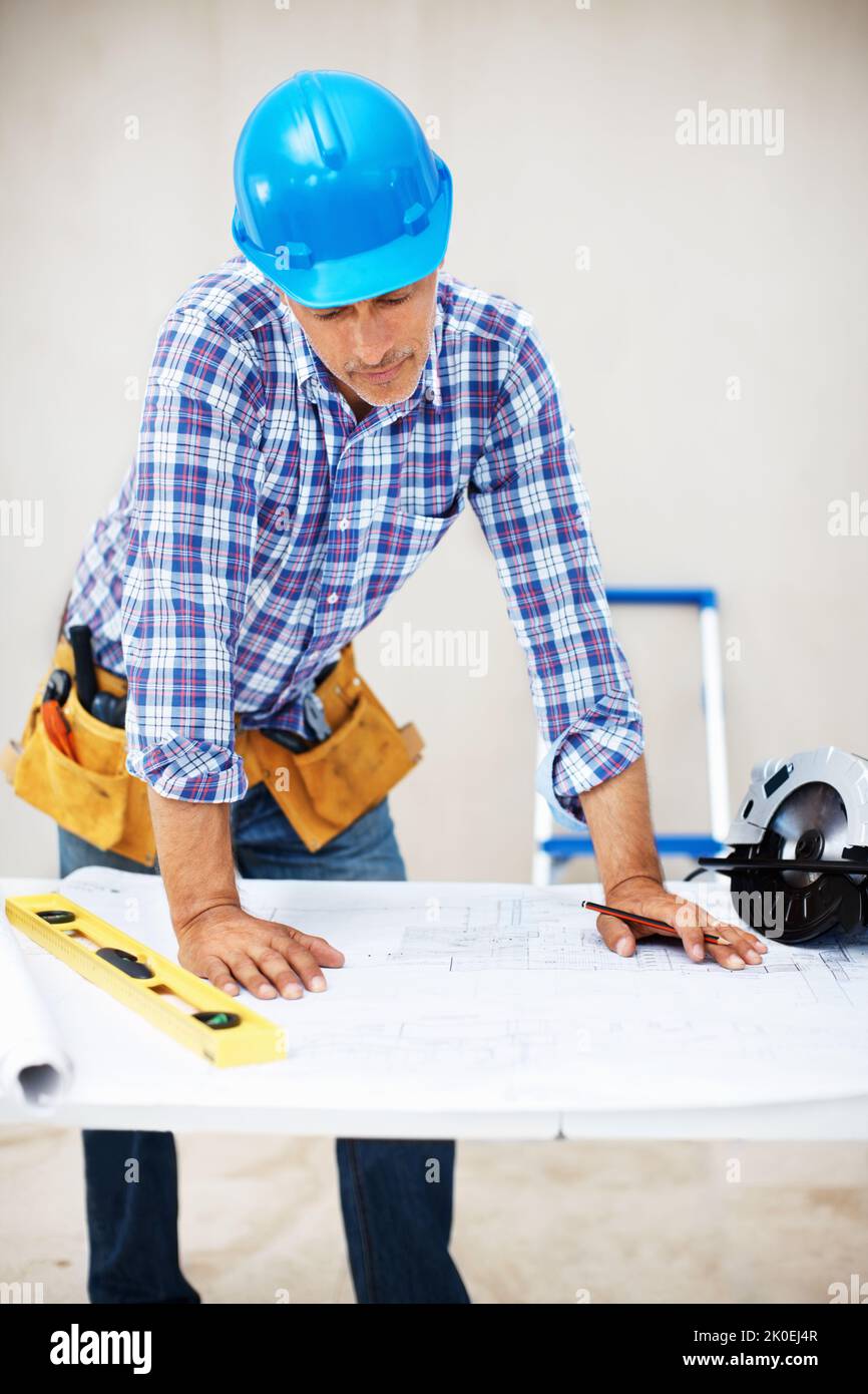 Engineer looking at blueprint. Mature engineer in hardhat looking at ...