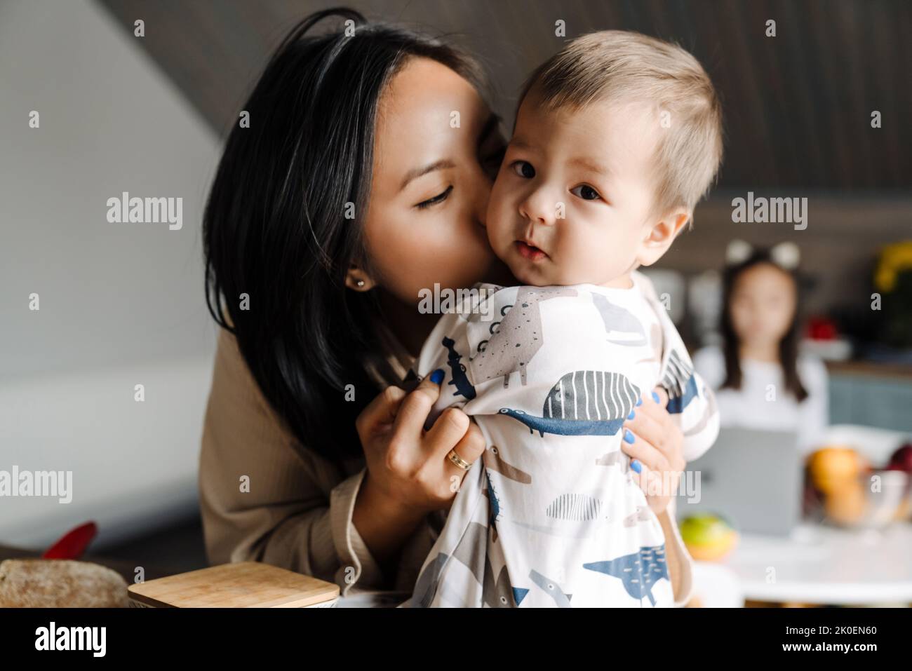 Happy mother kissing her son while cutting bread at home Stock Photo ...