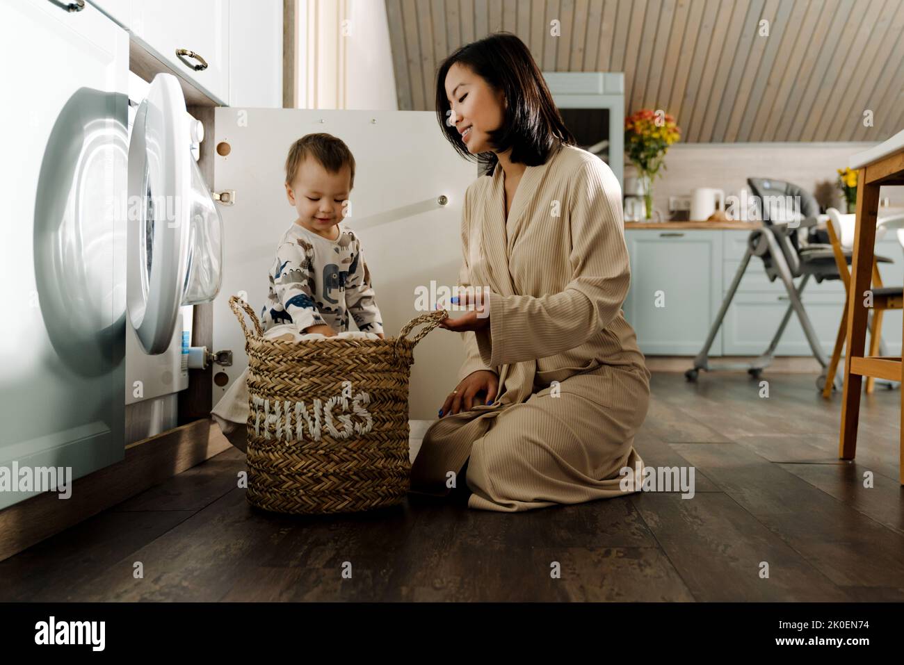 Happy mother smiling while doing housework with her son with her son at ...