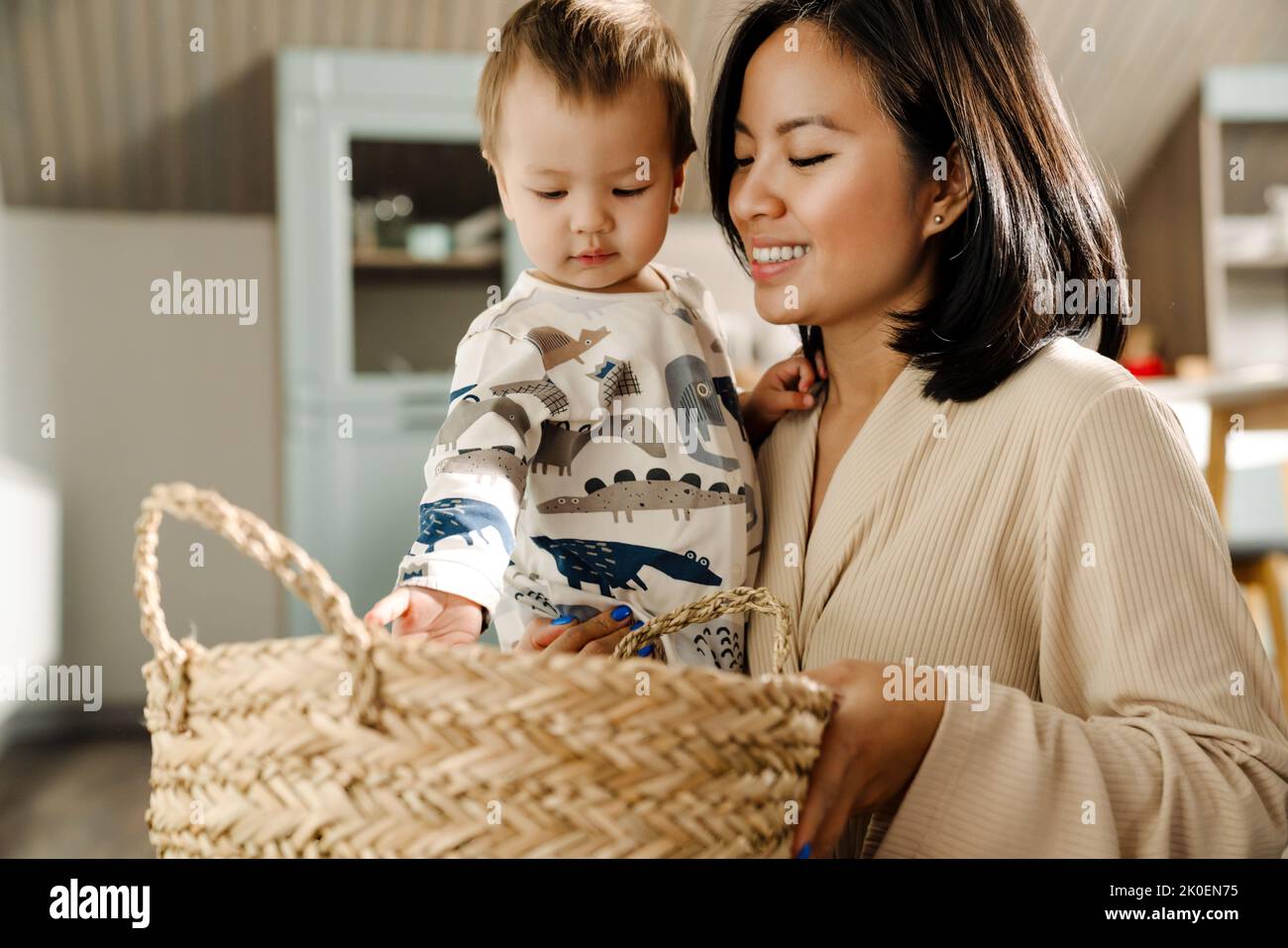Happy mother smiling while doing housework with her son with her son at ...