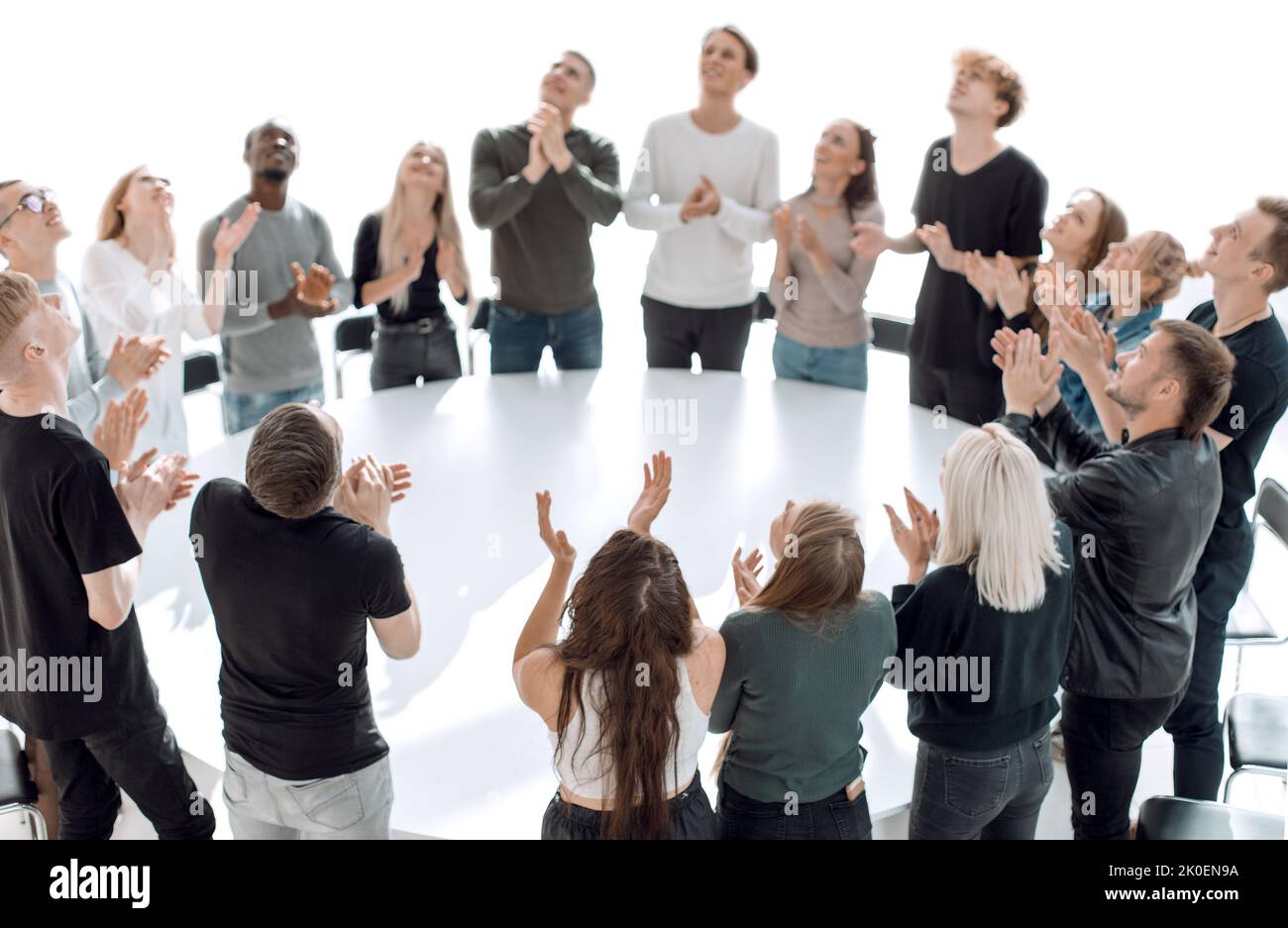 group of diverse young people standing around a round table Stock Photo ...