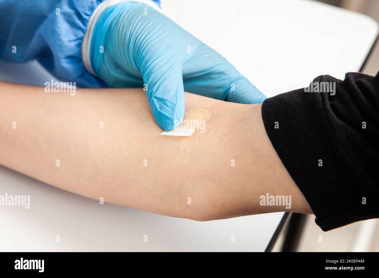 Nurse putting a Band-Aid on a patient's arm after taking a blood sample ...