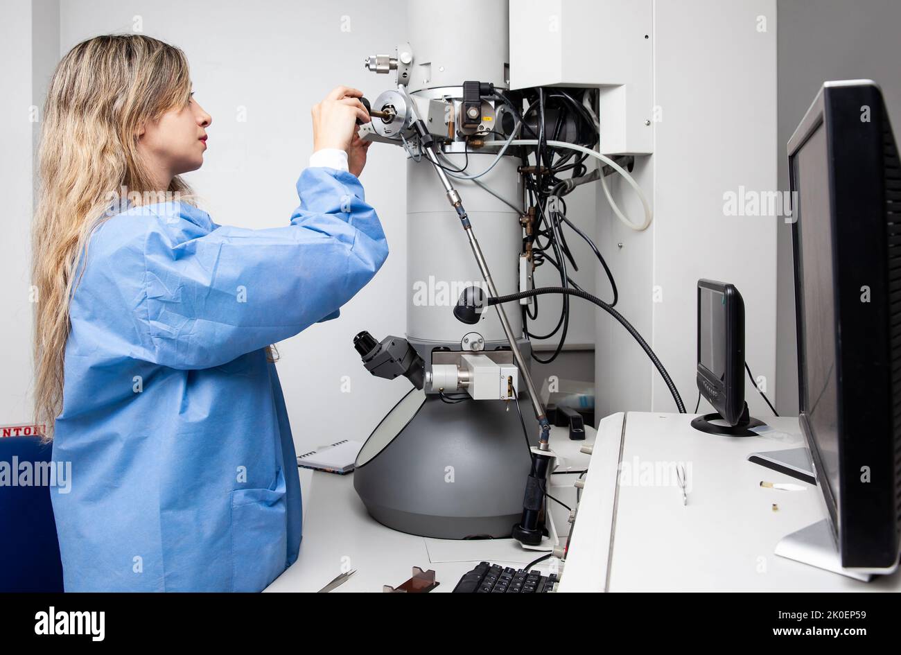Young female scientist loading a specimen using a sample holder into a ...