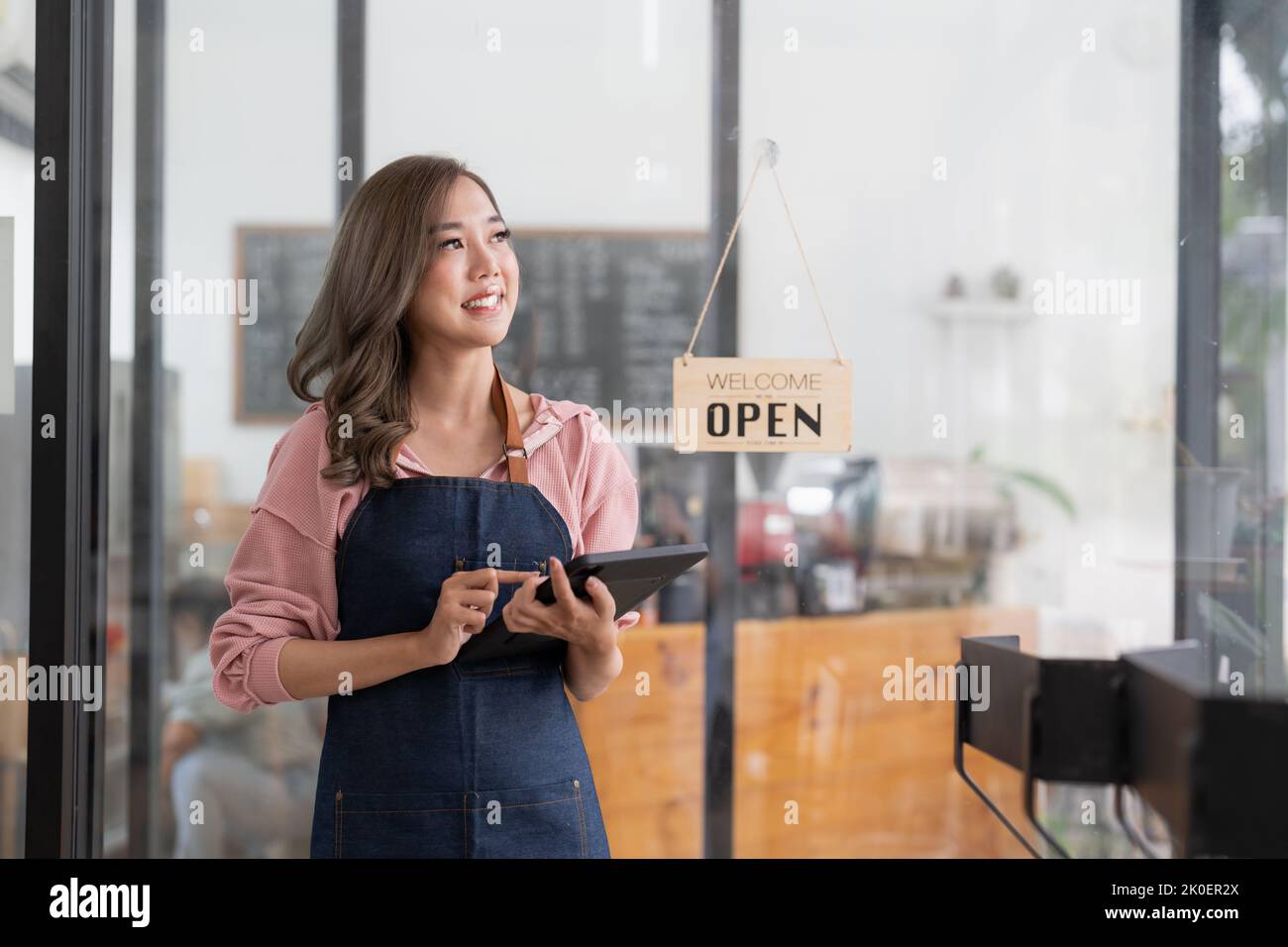 Young asian woman coffee shop owner wearing apron holding digital ...