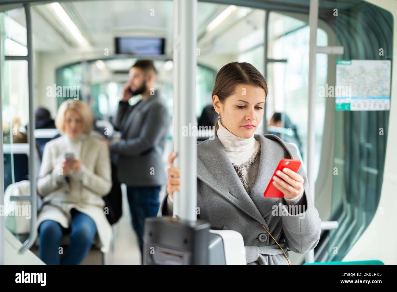 Positive woman reading from mobile phone screen in tram Stock Photo - Alamy