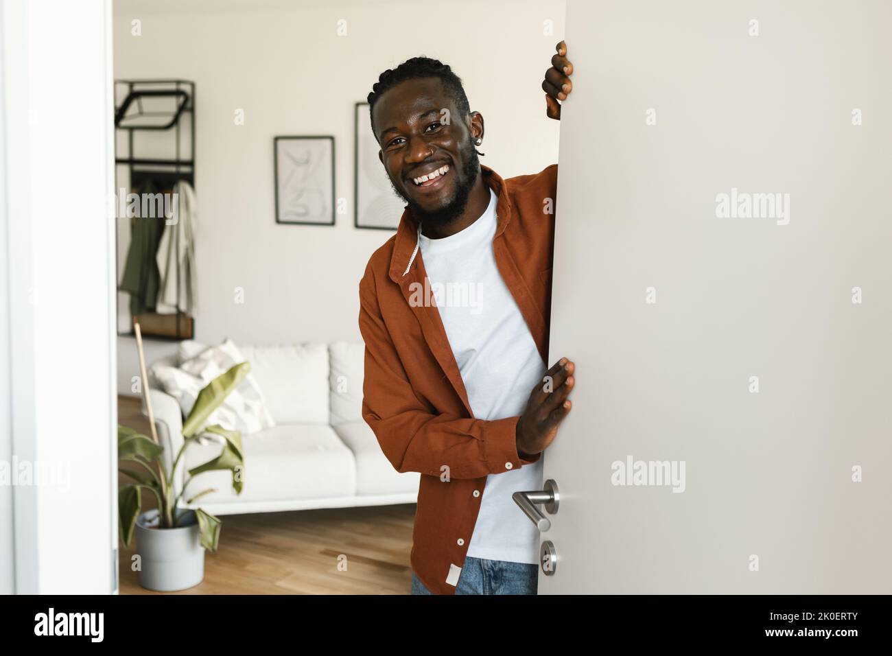 Cheerful african american man opening door and smiling to camera ...