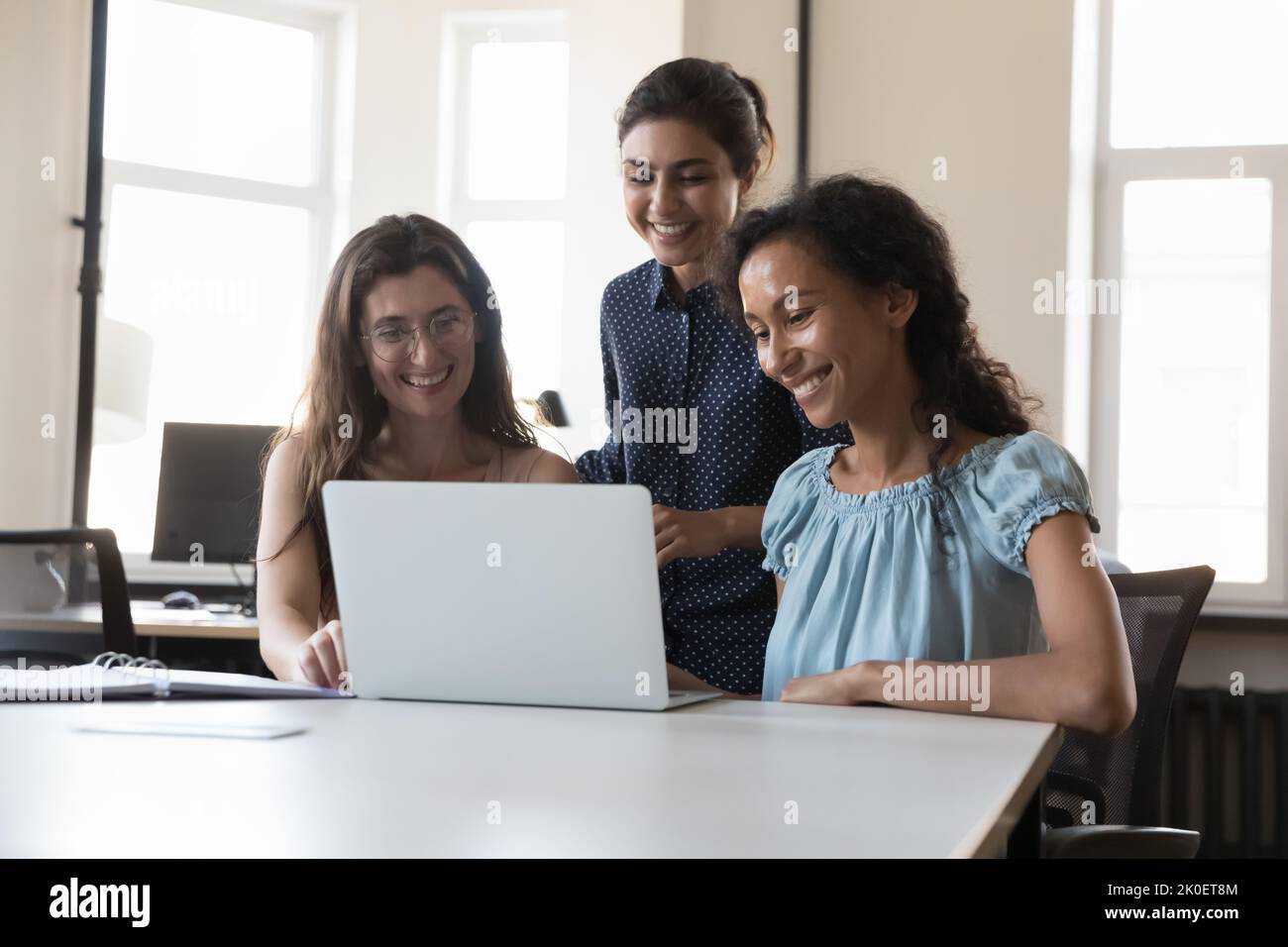 Happy successful diverse team of three employees women using laptop ...