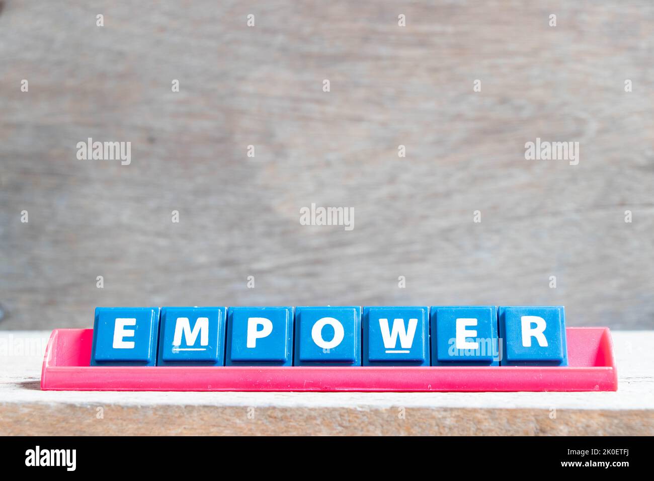 Tile alphabet letter with word empower in red color rack on wood ...