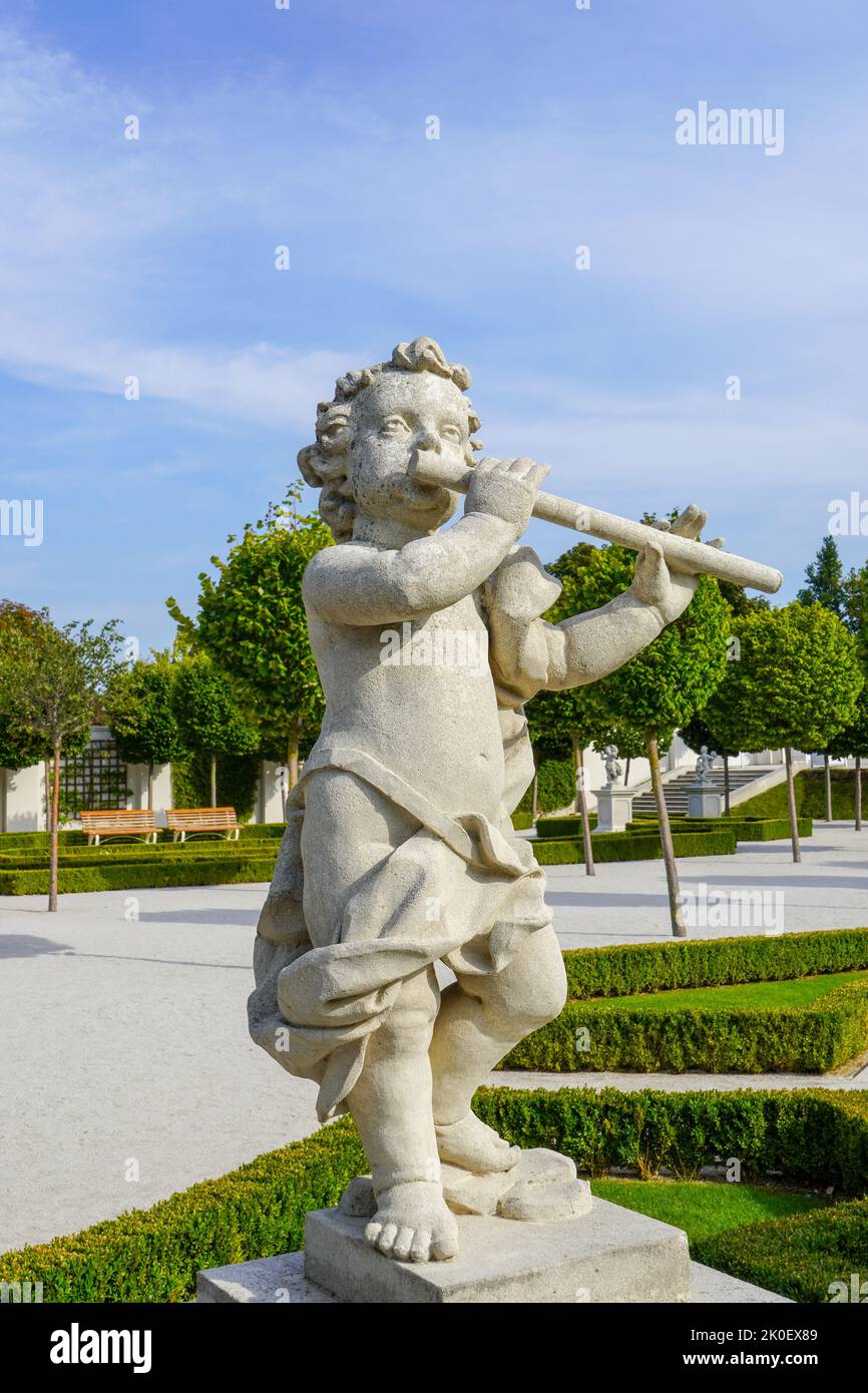 A statue of a little angel who plays the flute. Gray stone landscape ...
