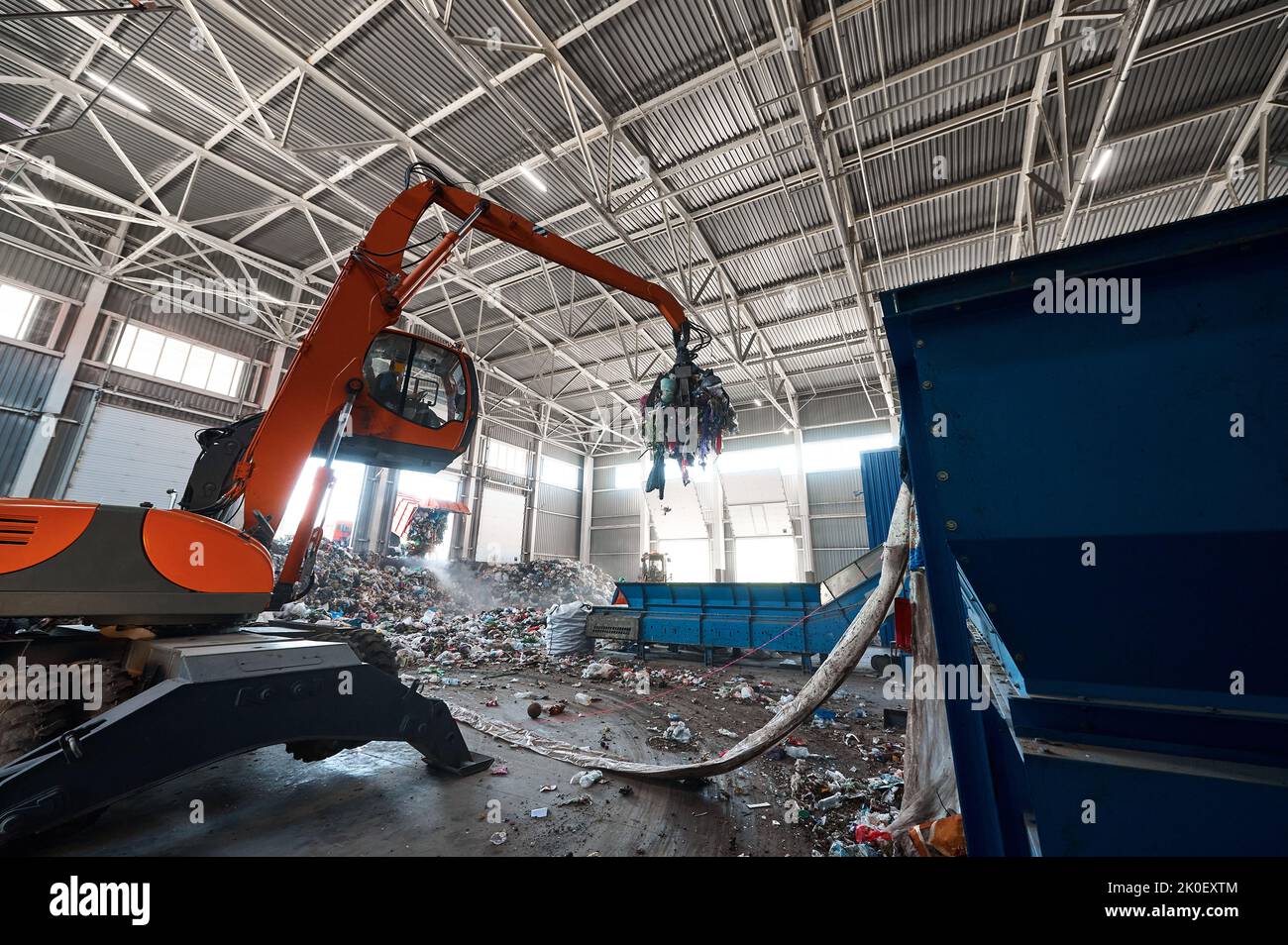 Excavator grabs trash in warehouse of waste processing plant Stock ...