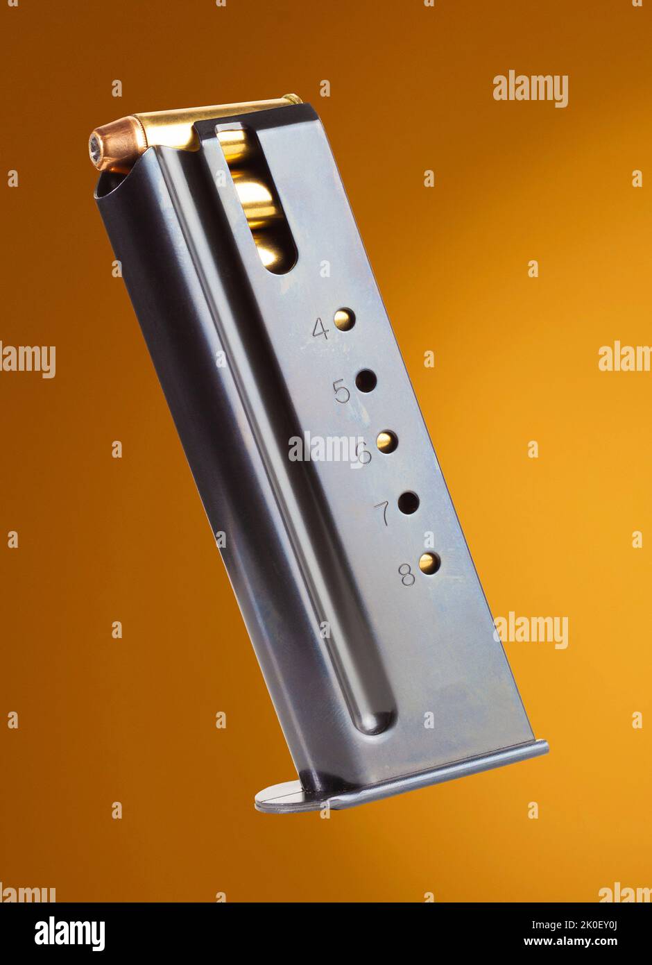 Handgun magazine filled with hollow point bullets on an orange ...