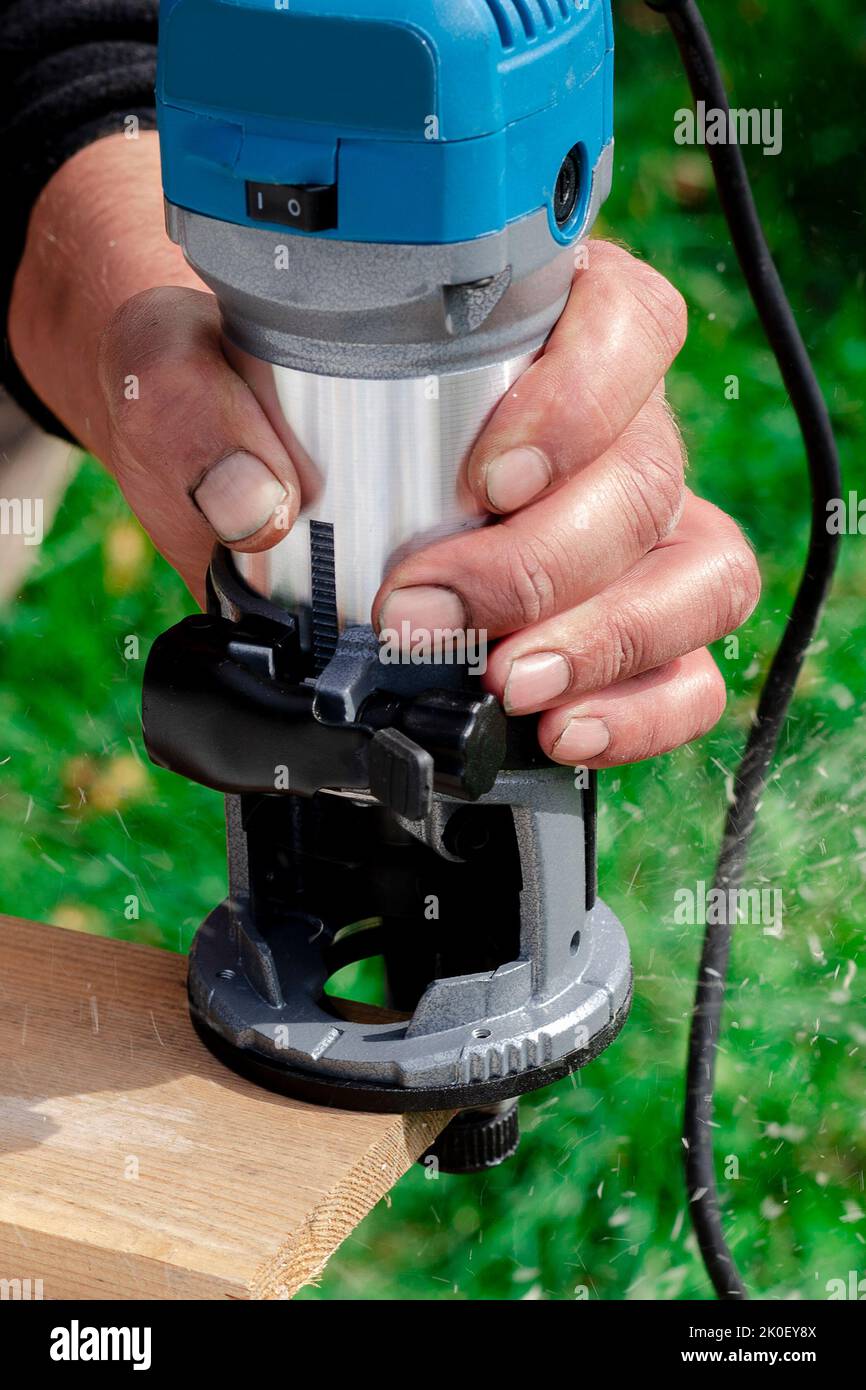 closeup of carpenter with hand wood router machine at work. closeup of ...