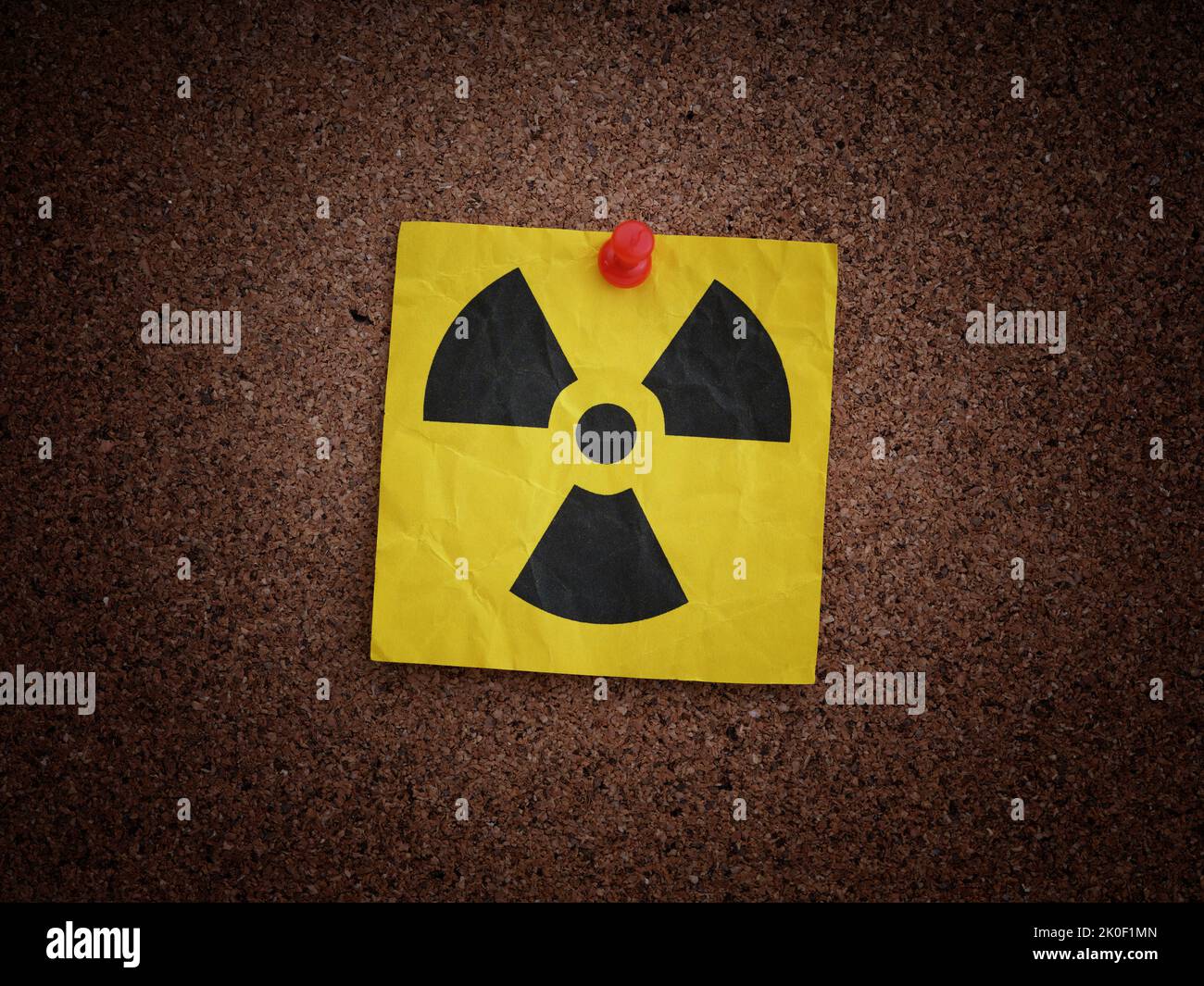 A yellow paper note with a radiation warning sign on it pinned to a ...