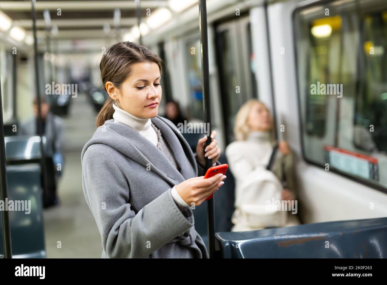 Young woman with phone in public transport Stock Photo - Alamy