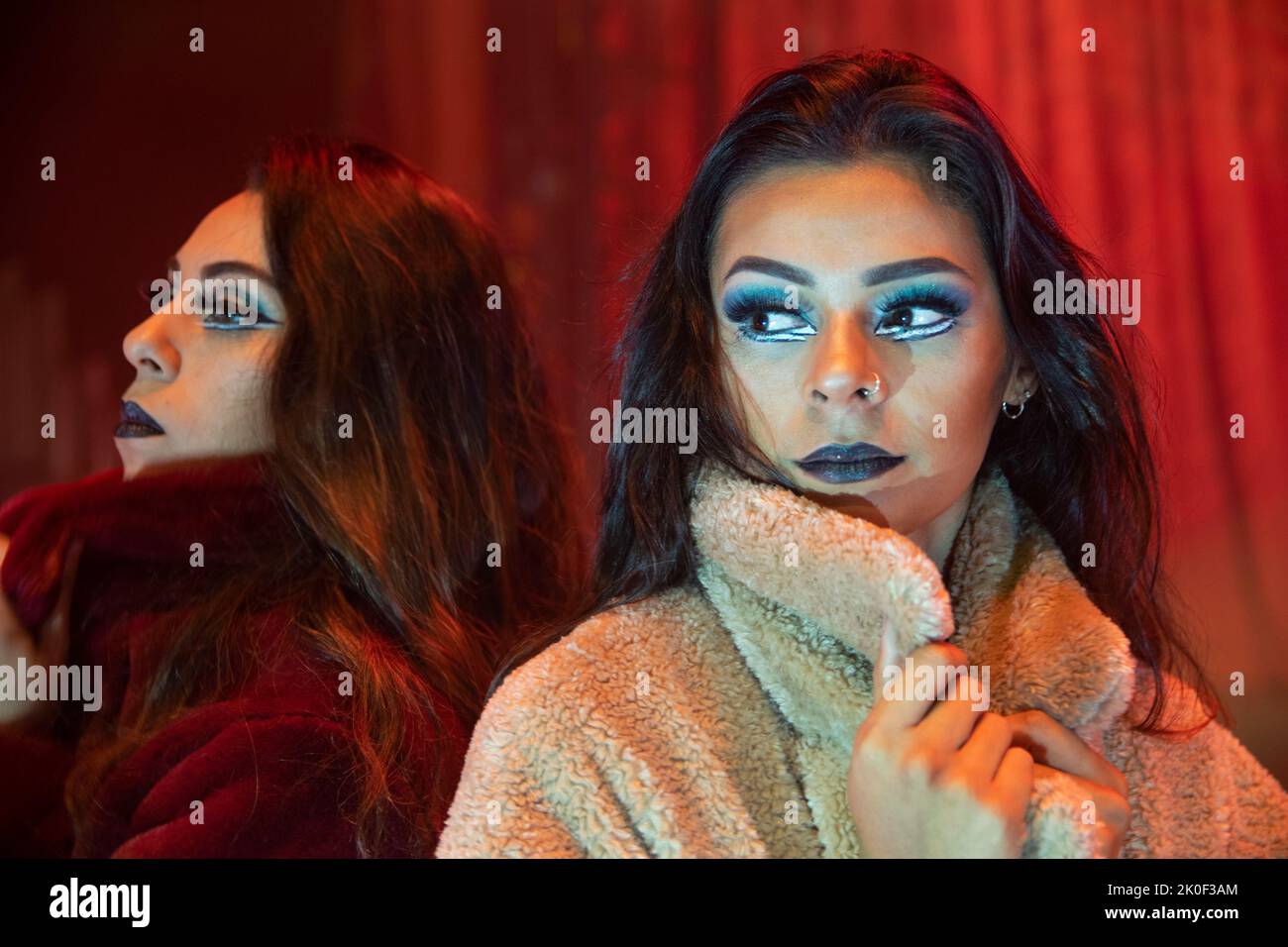 Two females with circus make up wearing winter faux fur coats against a ...