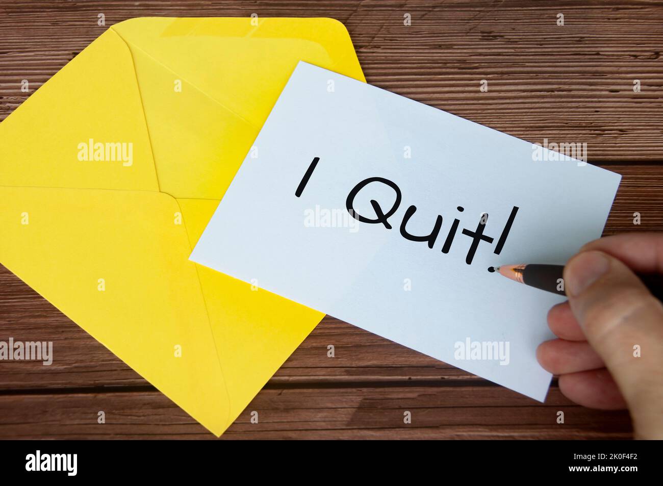 Hand writing I quit text on white notepad with yellow envelope ...